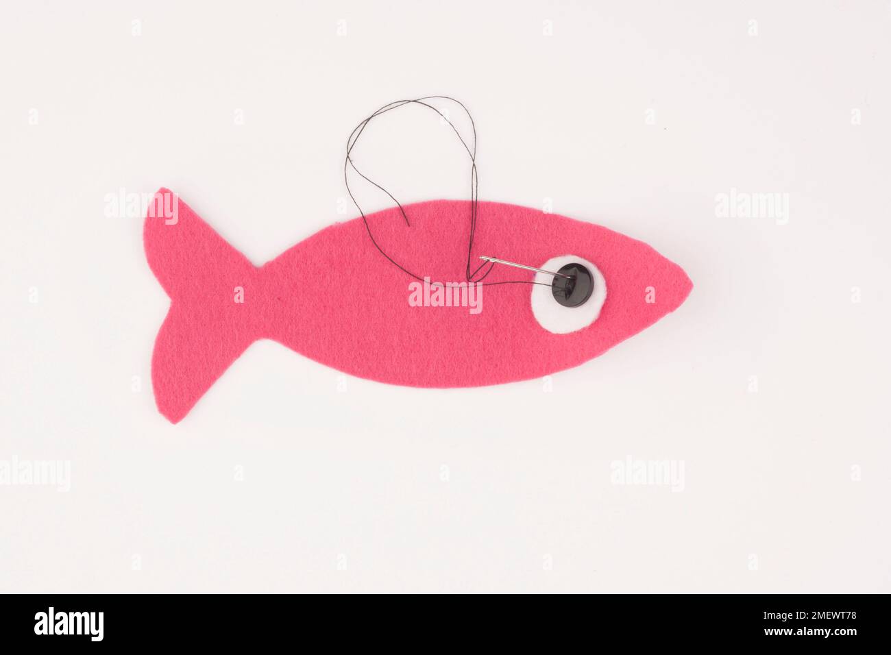 Sewing button 'eye' onto felt fish Stock Photo - Alamy