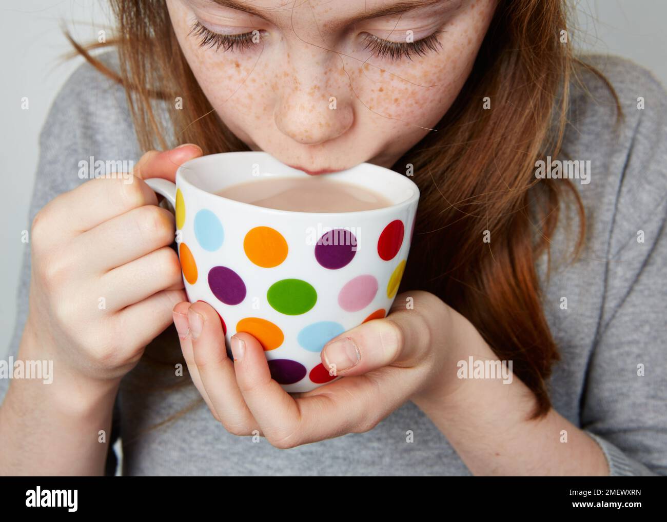 Child drinking a hot drink from a spotty mug Stock Photo - Alamy