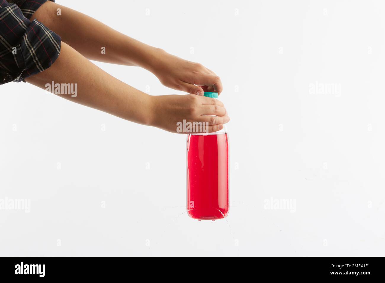 Plastic bottle of red liquid held in two hands Stock Photo - Alamy