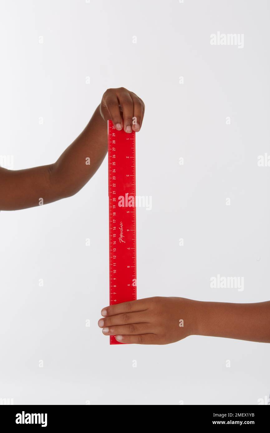 Red ruler is held by two hands as part of a reactions test Stock Photo ...