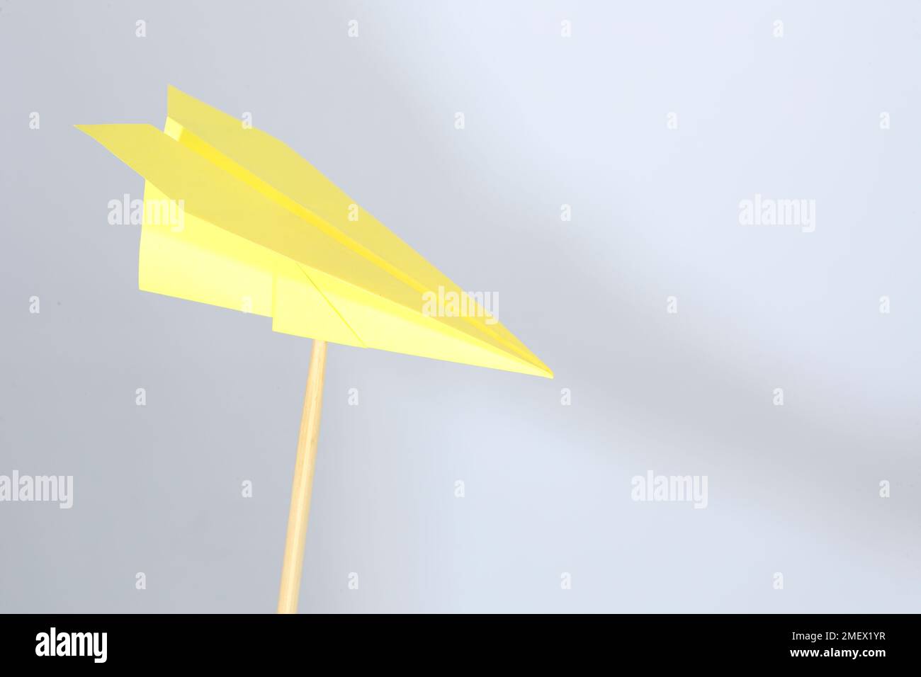 Paper plane made of coloured paper and supported by a wooden stick ...