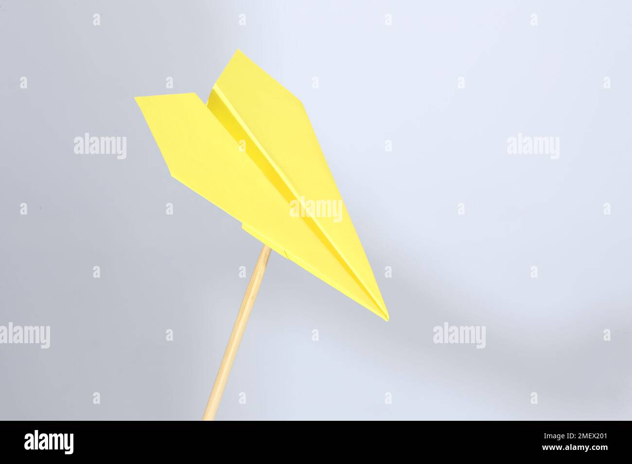 Paper plane made of coloured paper and supported by a wooden stick ...