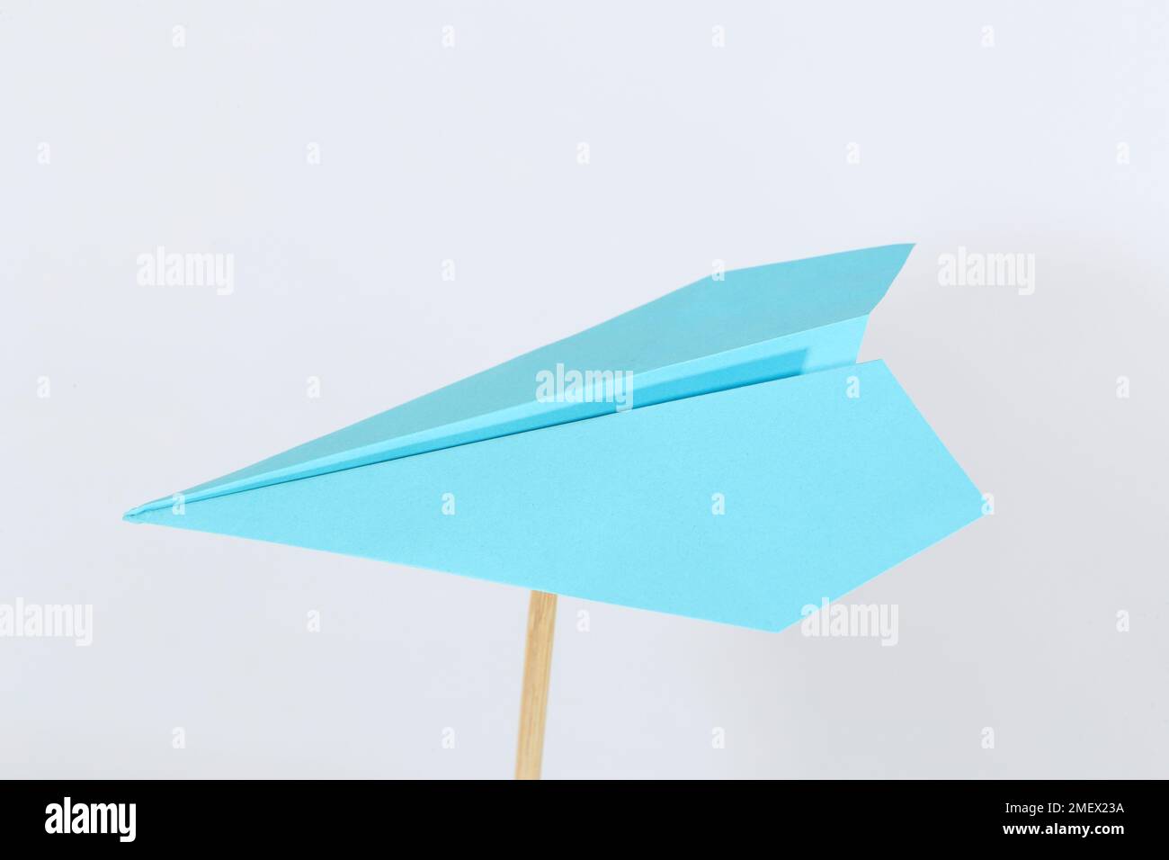 Paper plane made of coloured paper and supported by a wooden stick ...