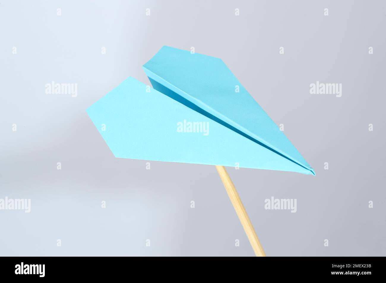 Paper plane made of coloured paper and supported by a wooden stick ...
