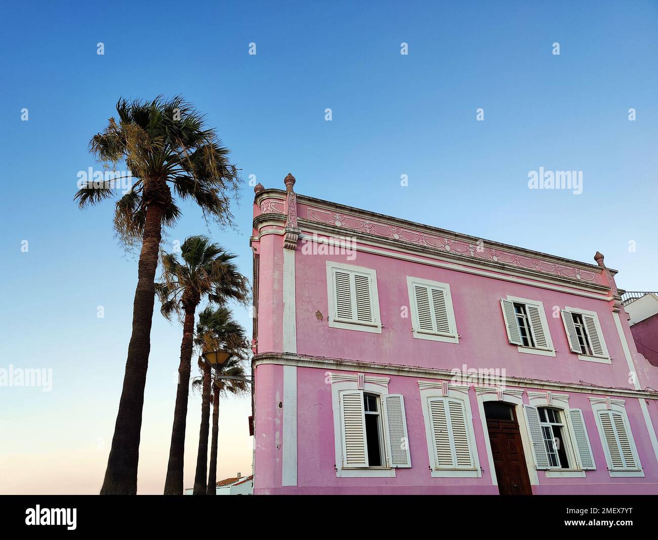 Sun setting over an old appartment house flanked by palm trees in ... Sun setting over an old appartment house flanked by palm trees in ...