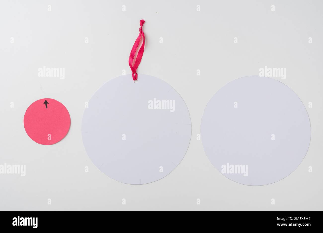 Pink paper circle with arrow on, two white paper circles on with a ...