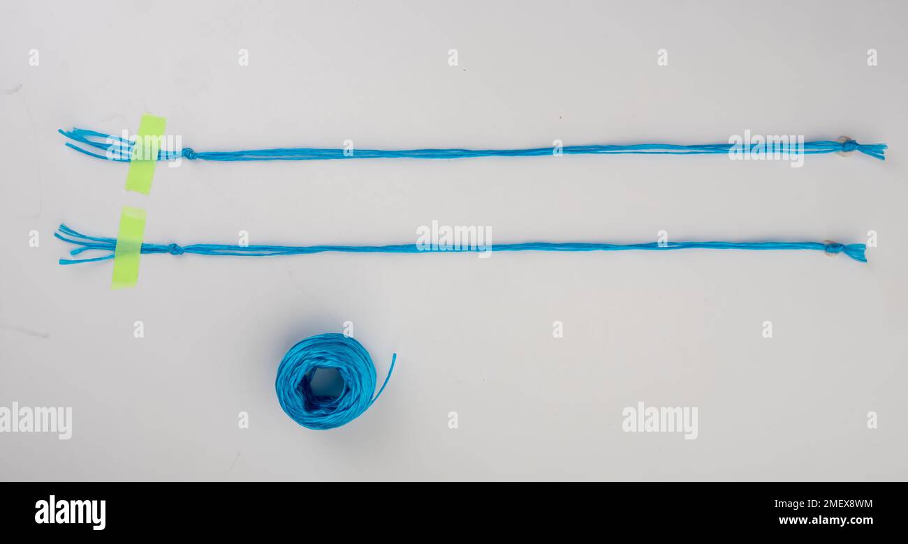String tied with knots on both ends held by tape and ball of string ... String tied with knots on both ends held by tape and ball of string ...
