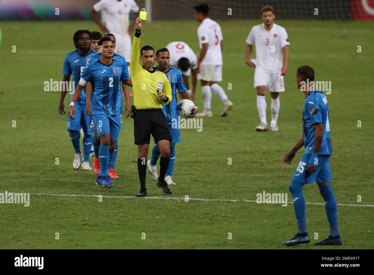 Referee Cesar Ramos from Mexico, center, shows a yellow card to ...