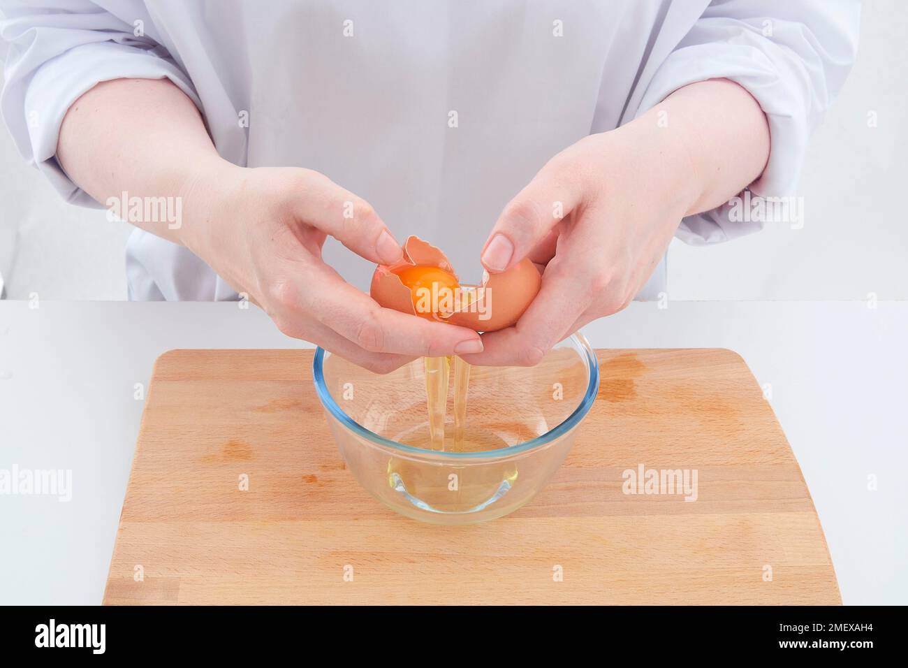 Cooking techniques - Separating an egg, pull both sides of shell apart gently Stock Photo - Alamy