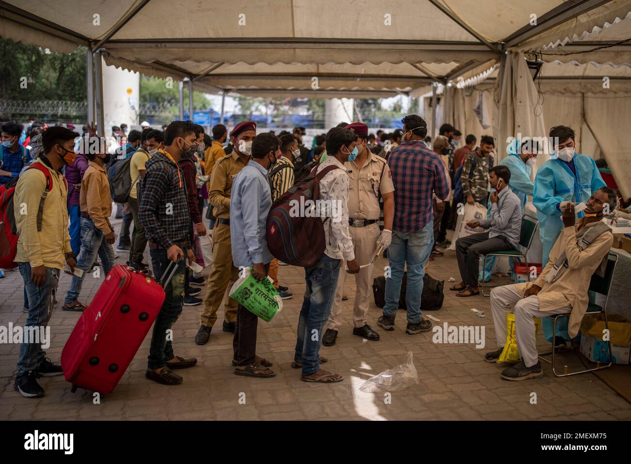 Passengers await their turn to be tested for COVID-19 at a bus terminal ...