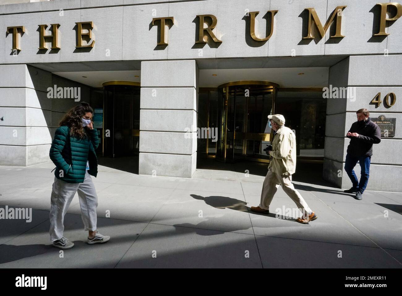 Pedestrians walk past the Trump building on Wall Street in New York's ...
