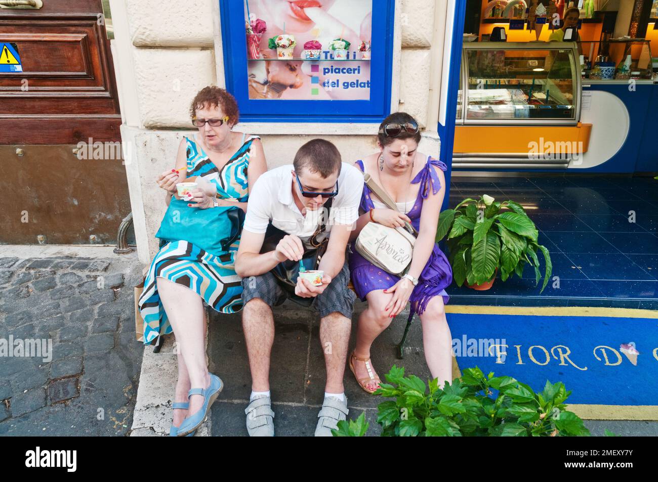 Mother with son and daughter eating ice cream outside gelato shop in ...