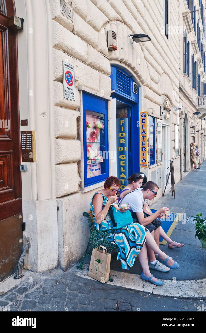 Mother with son and daughter eating ice cream outside gelato shop in ...