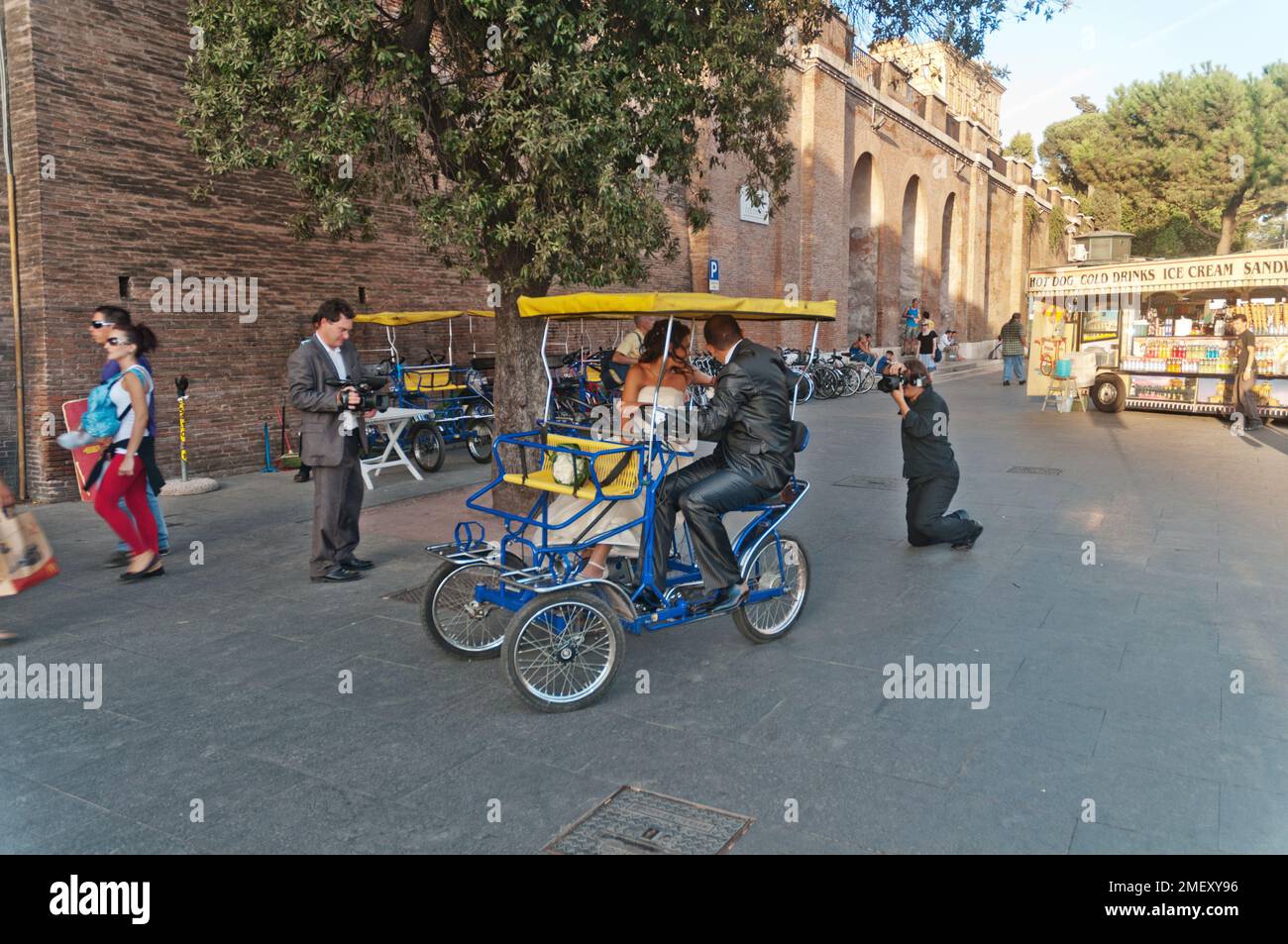 Bride and groom being photographed in a four wheel bike near Colosseum ...