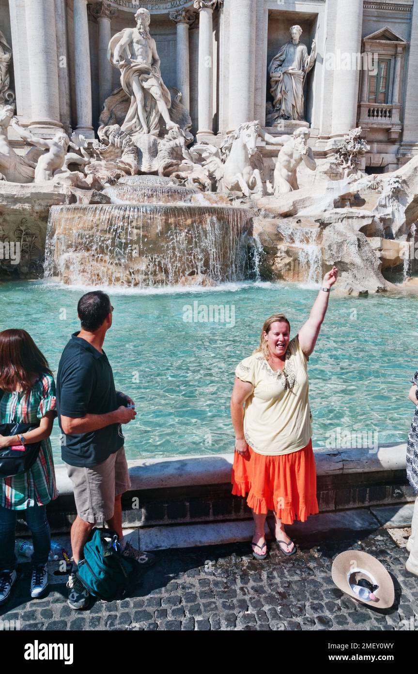 A woman getting ready to throw coins over her shoulder into the Trevi ...