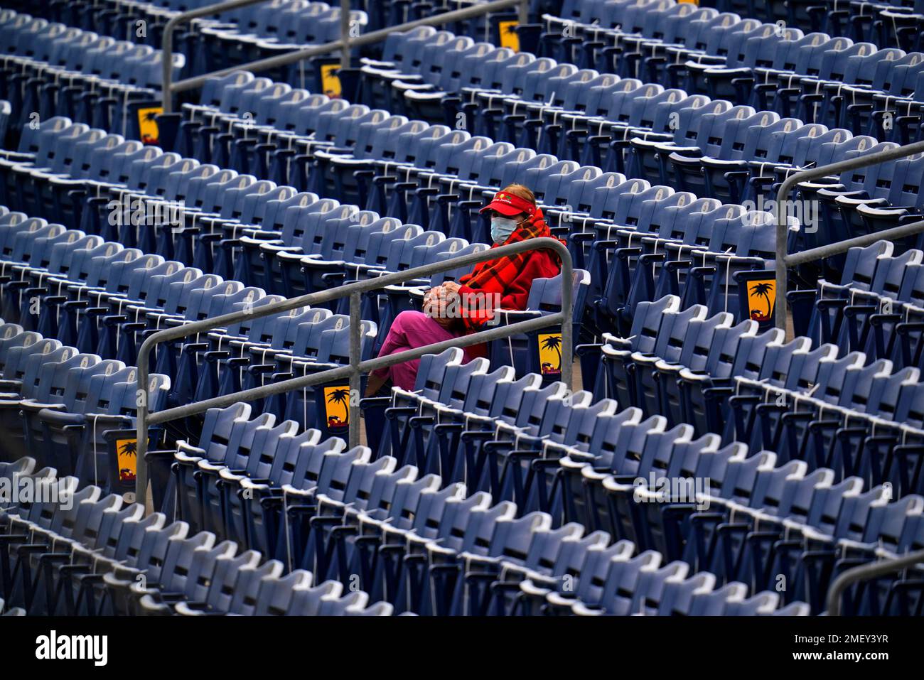 A limited number of socially distanced baseball fans watch a spring ...