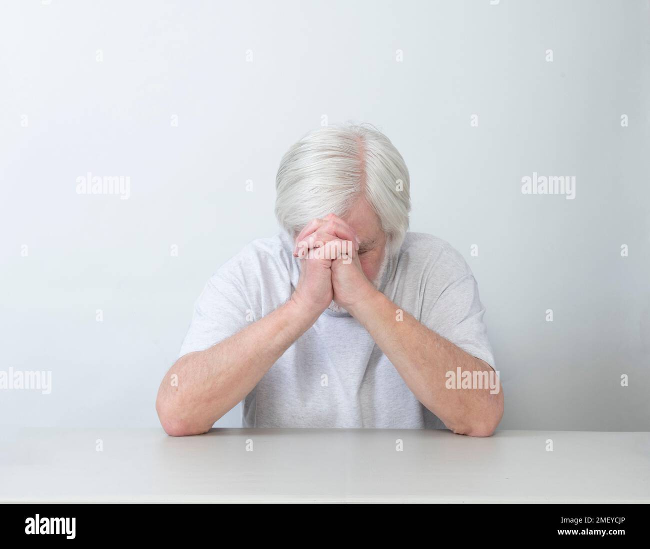 Horizontal shot of a white haired man sitting alone in sadness, prayer ...
