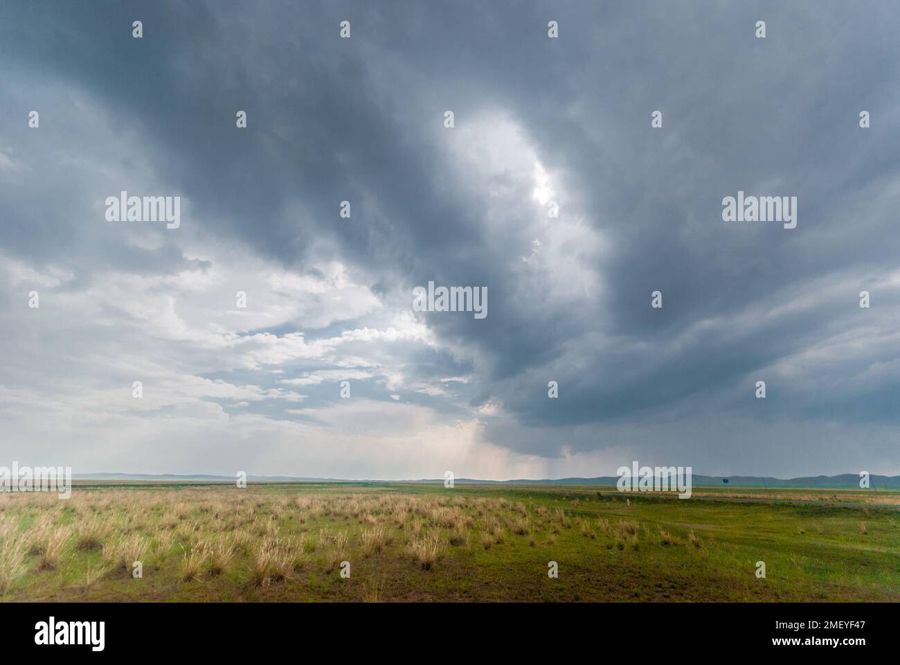 A beautiful view of a dirt path between green meadows under a dramatic ...