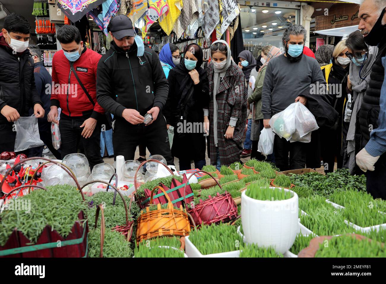 Potential customers look at baskets of grass shoots, an item of the ...