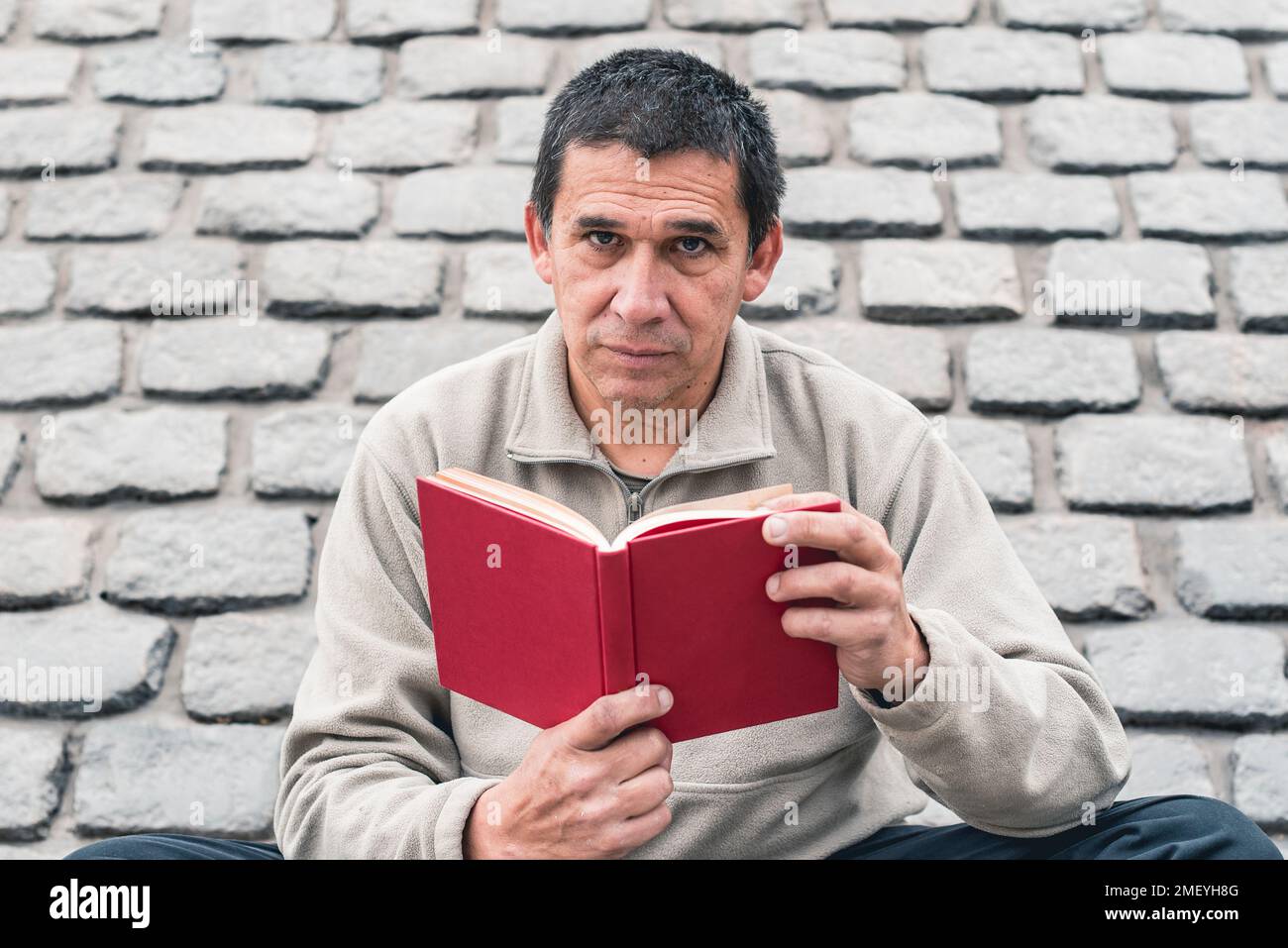 An adult man reading a red book outdoors Stock Photo - Alamy