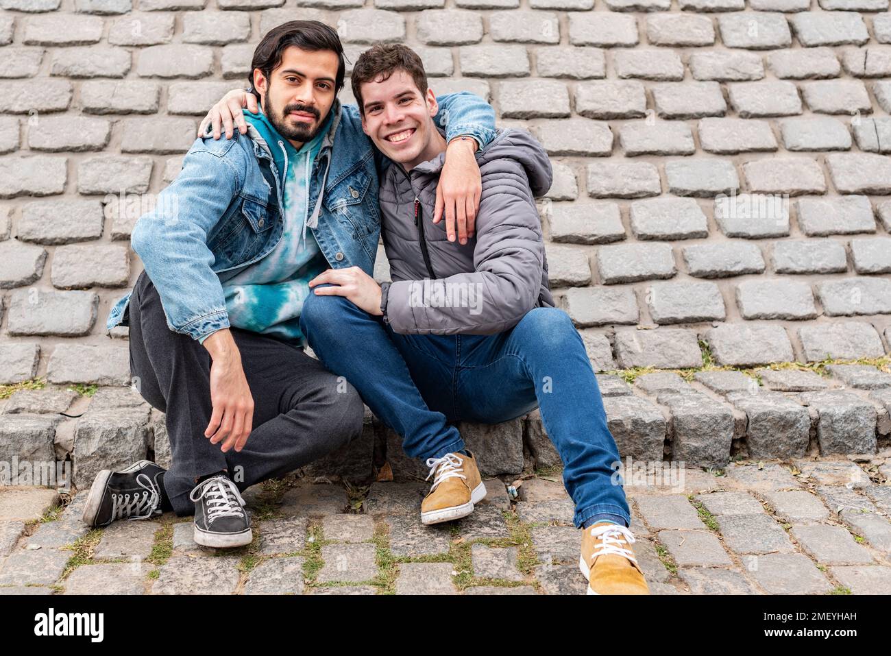 Two male friends hugging and looking at camera outdoors Stock Photo - Alamy