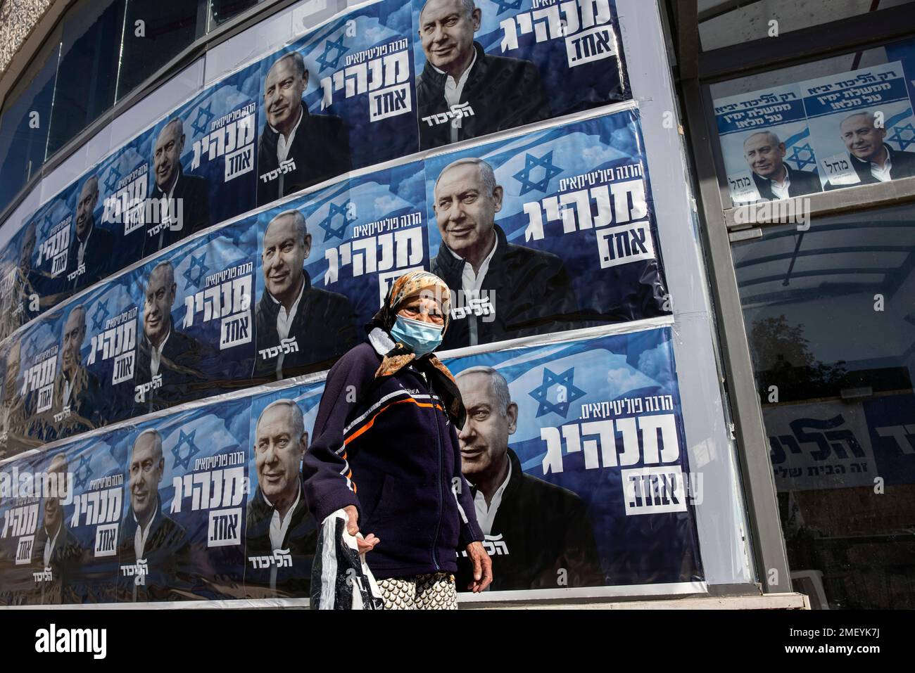 A woman passes Likud party campaign posters for Prime Minister Benjamin ...