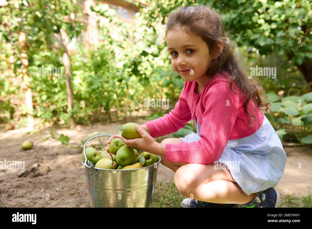 Lovely child girl, wearing blue summer dress and pink bolero, stacking ...