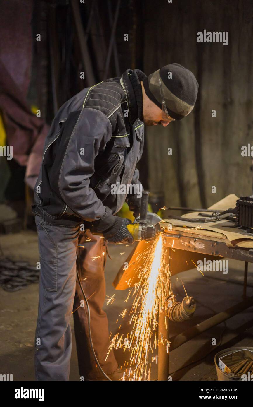 Blacksmith sawing metal with hand circular saw Stock Photo - Alamy