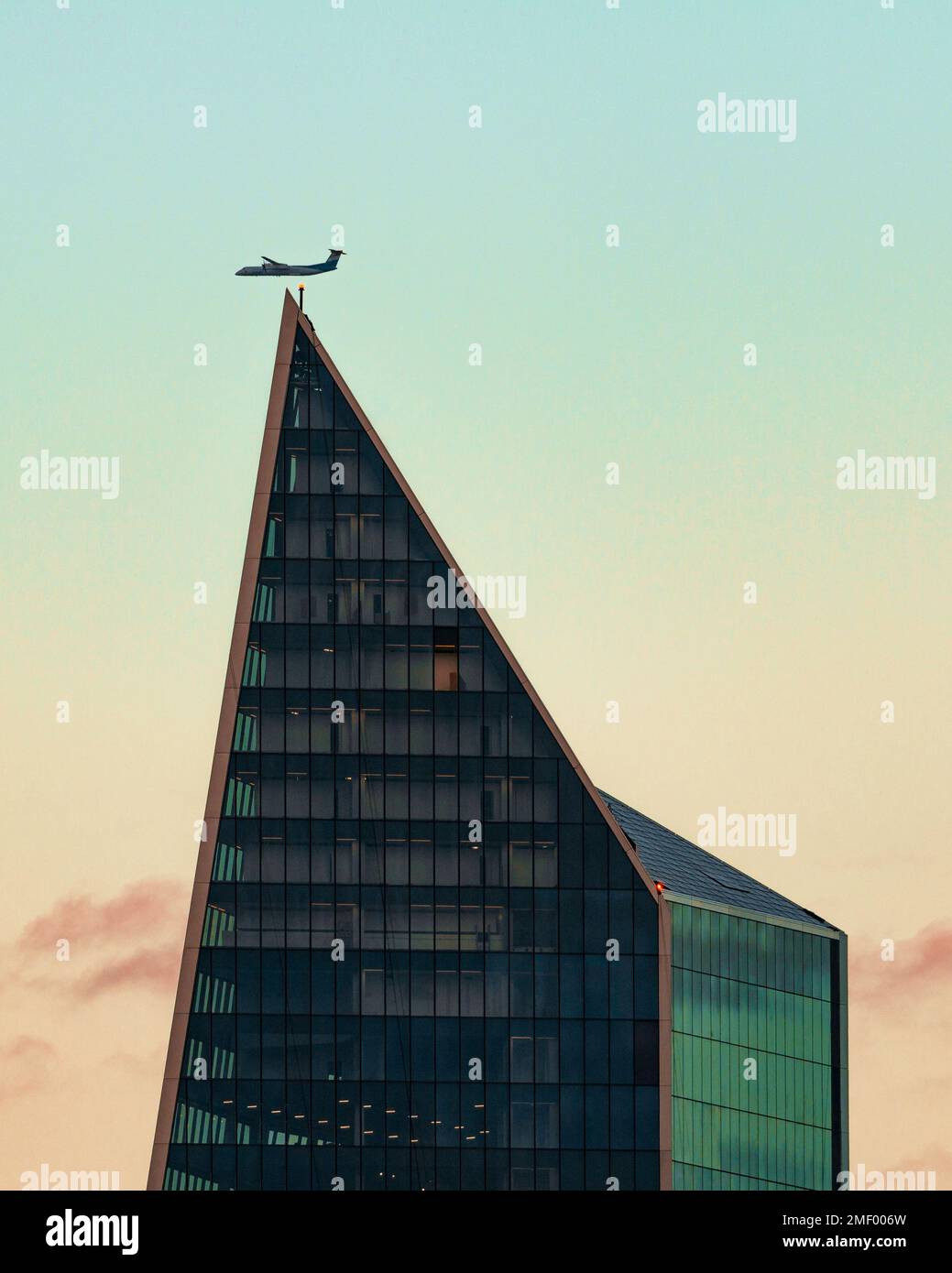 A vertical shot of a plane flying above a modern office building during ...