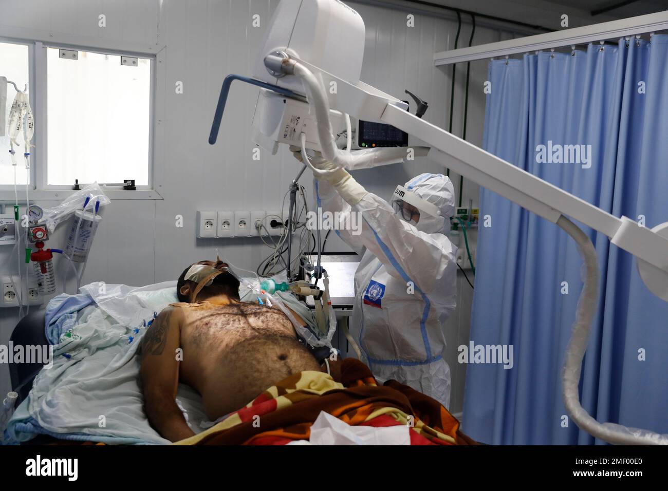 A healthcare worker takes a radiograph of a COVID-19 patient in an ...