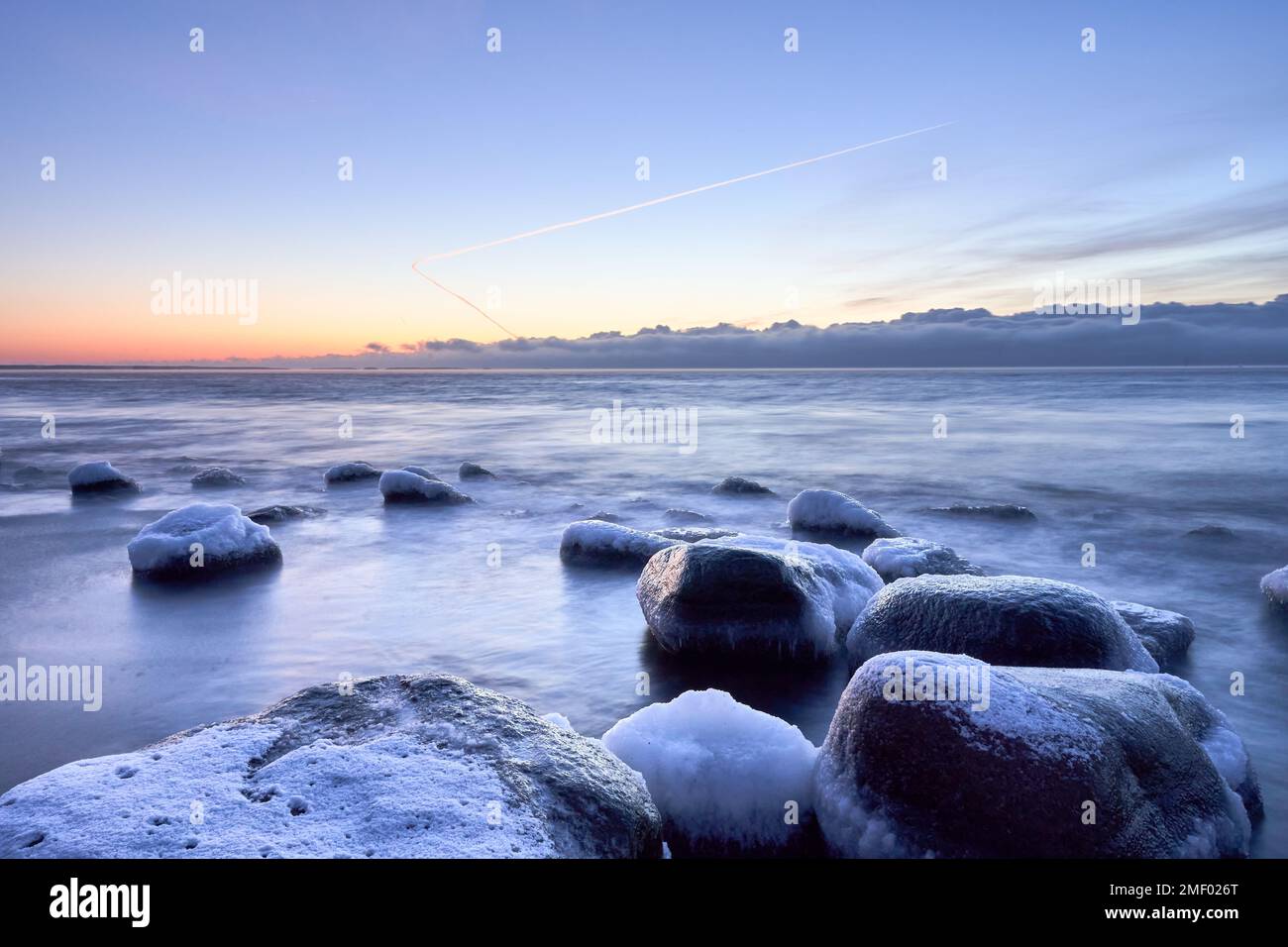 A high angle shot of frozen rocks covered in snow near a frozen lake ...