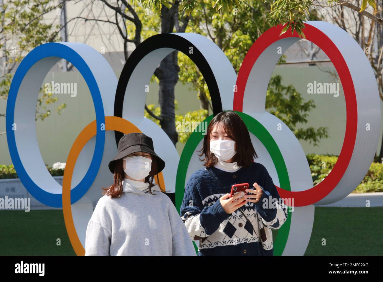 People walk past the Olympic rings in Tokyo, Wednesday, March 17, 2021 ...