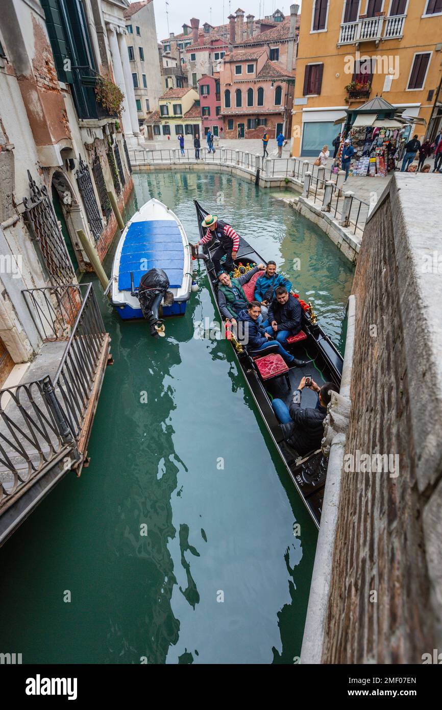 Group of male tourists enjoying a gondola ride in the canals of Venice ...