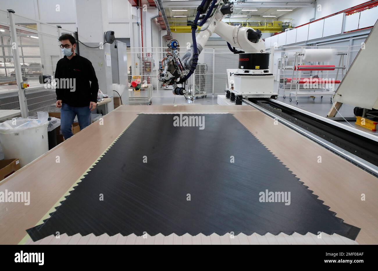 A worker prepares a machine used in aerospace engineering to cut a ...
