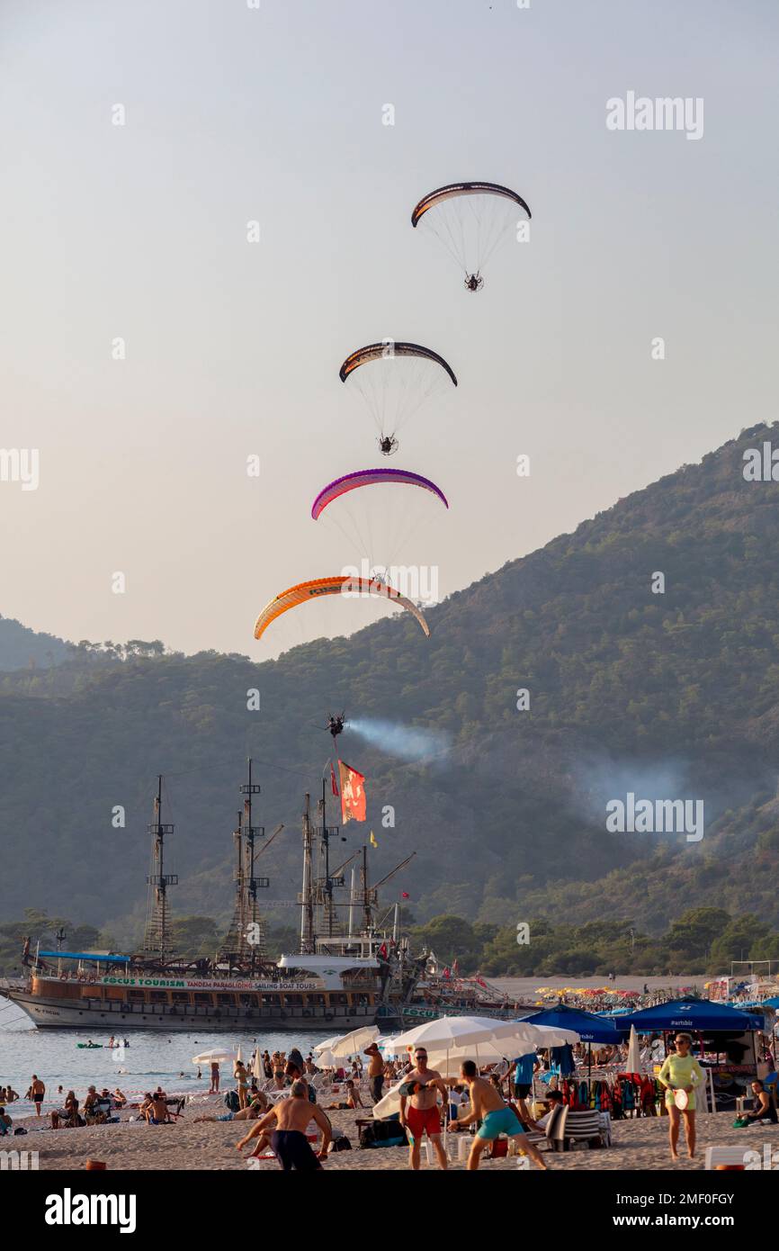 Paramotor pilots flying over boats and beachgoers in Belcekiz Beach ...