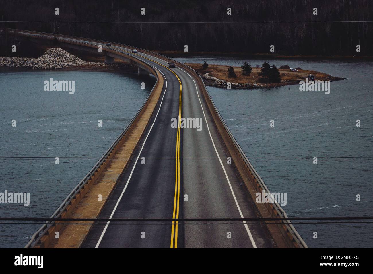 An aerial shot of cars driving on a road built on a bridge over a lake ...