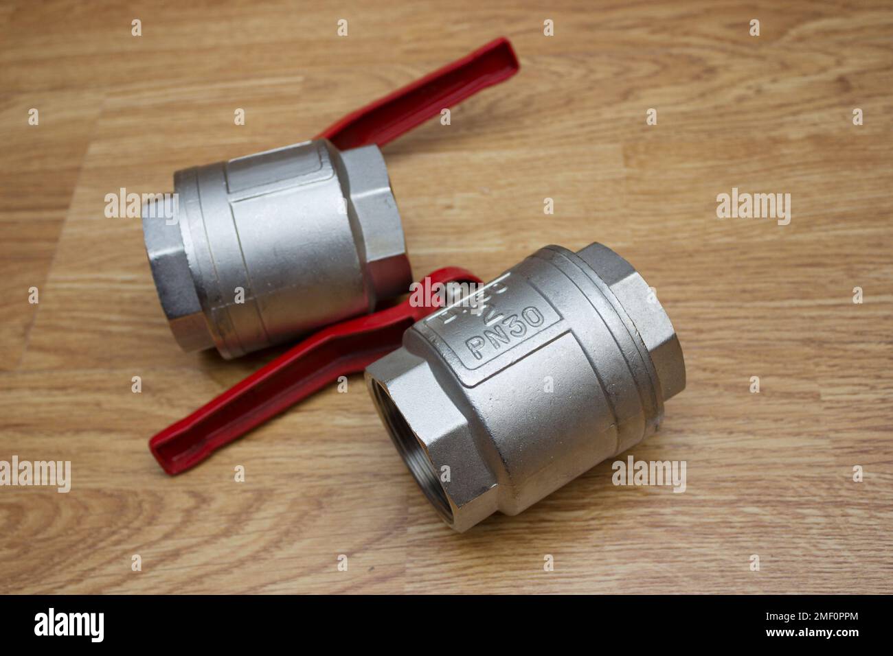 A pair of large two-inch ball valves with a red lever handle lie on a ...