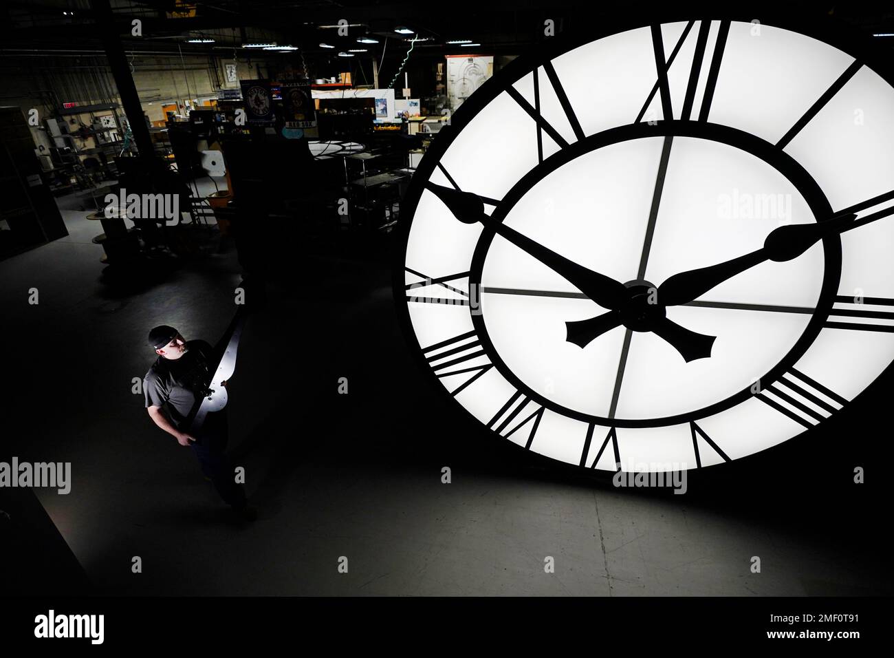 Electric Time technician Dan LaMoore carries a clock hand on the plant ...