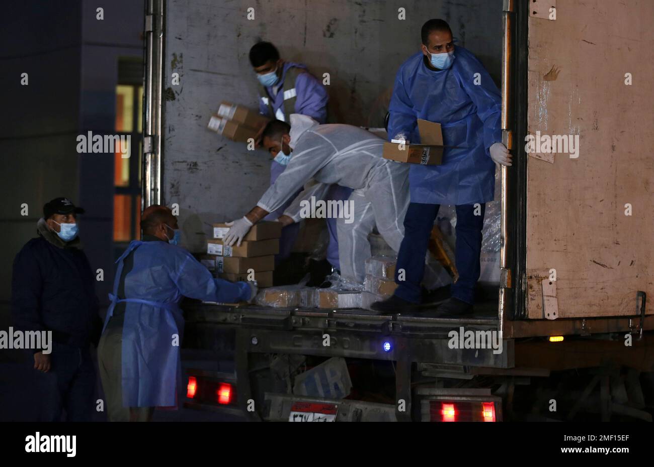 Hamas police officer stands near truck while medic workers unload a ...