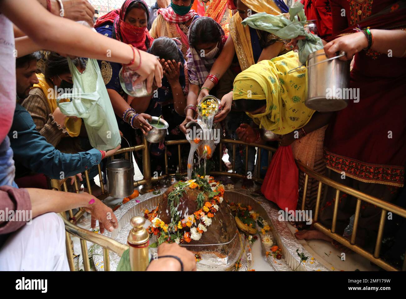 Indian devotees perform ritual in front of a Shivling, a representation ...