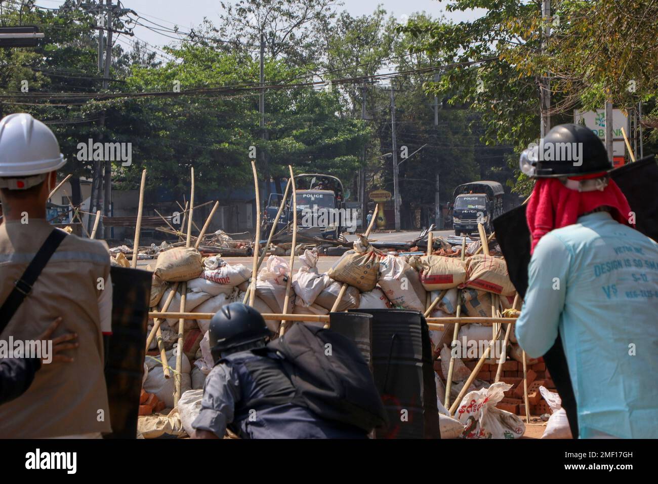 Anti-coup protesters take cover behind makshift barricades as trucks ...