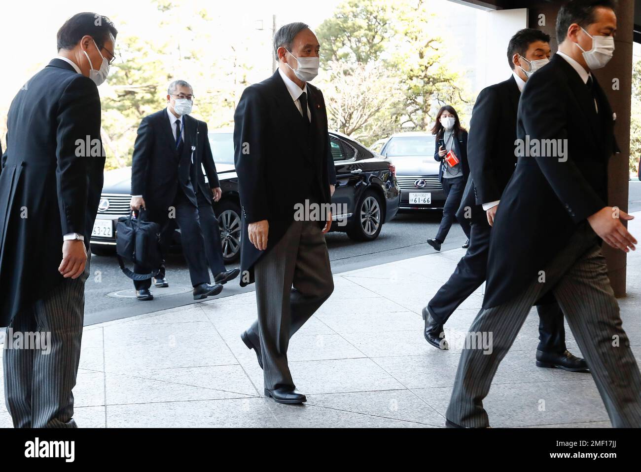 Japan's Prime Minister Yoshihide Suga, center, wearing a face mask ...