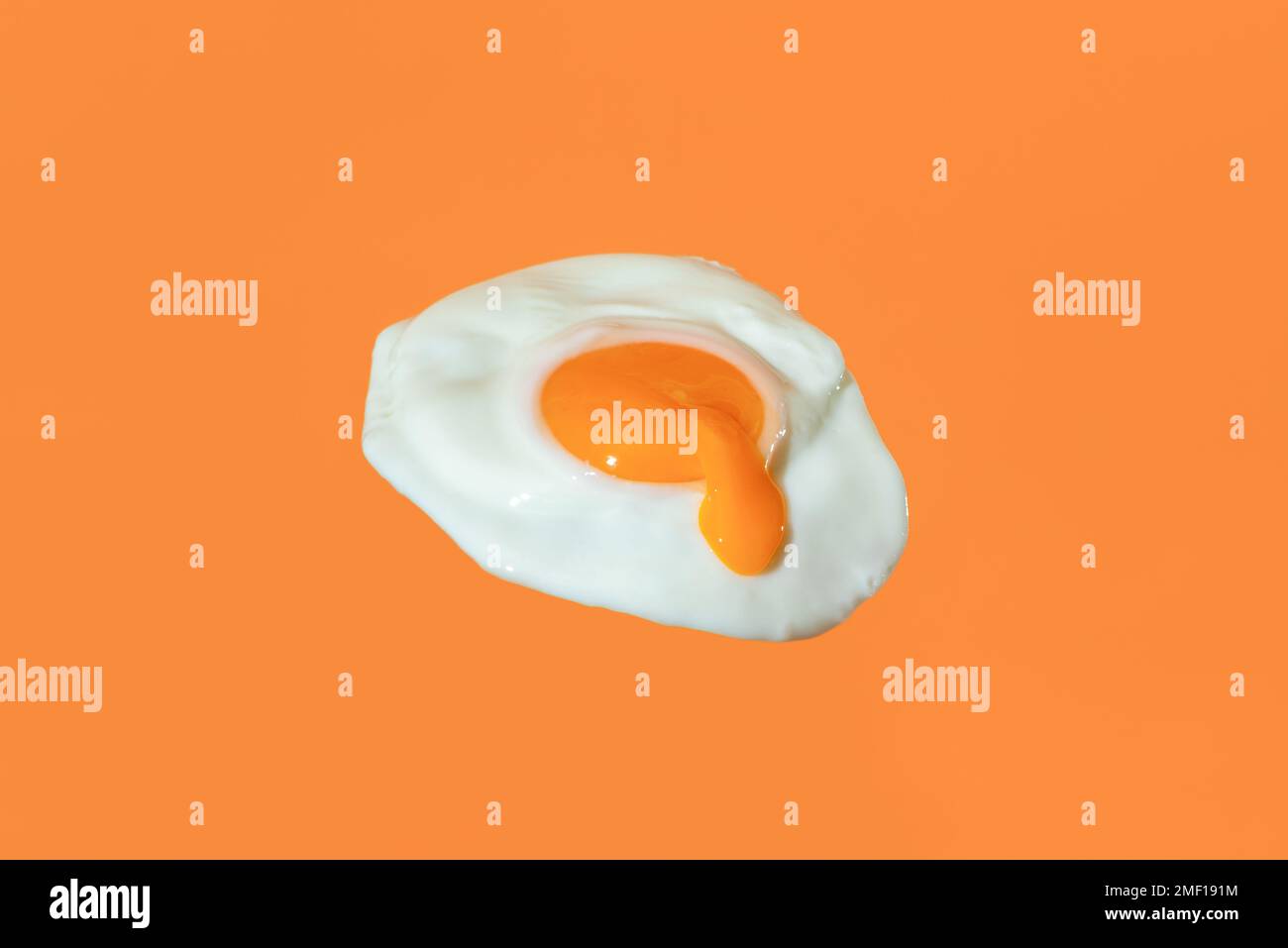 Close-up with a single sunny side up egg isolated on an orange ...