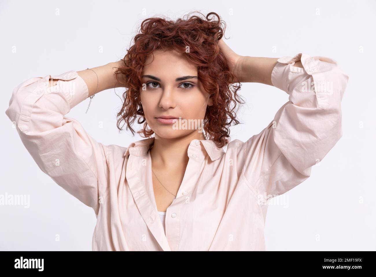 The girl corrects her curly hair with two hands. European Stock Photo ...