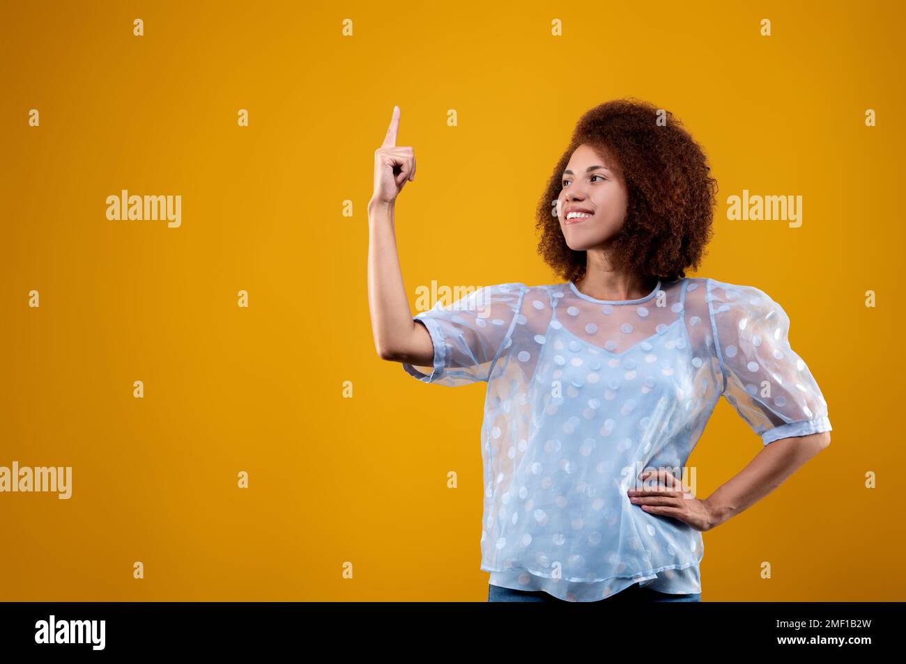 Cute young woman in a white blouse pointing her finger up Stock Photo ...