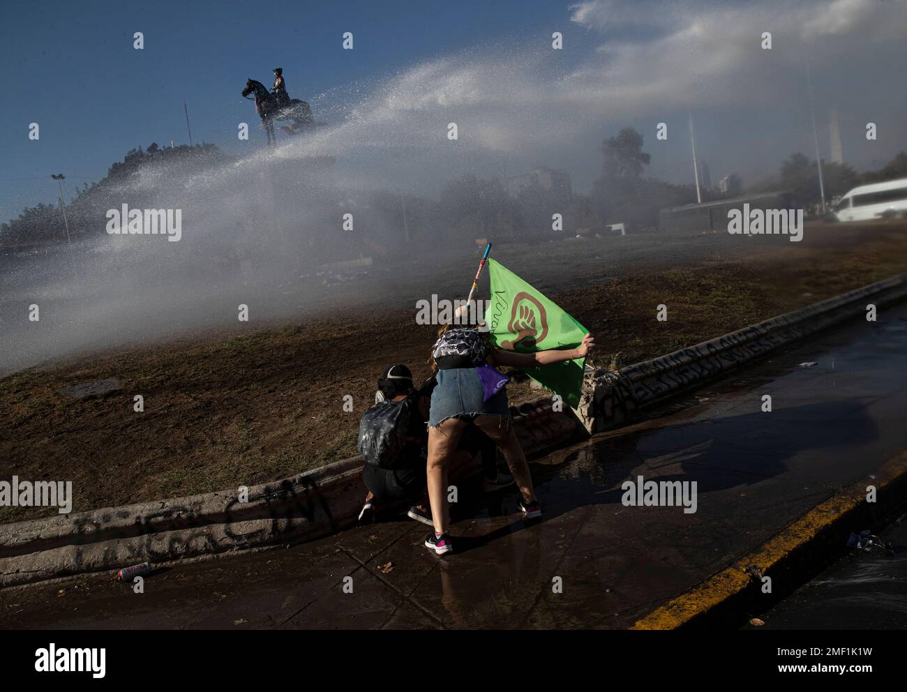 Women take cover from the jet of a police water cannon during a protest ...