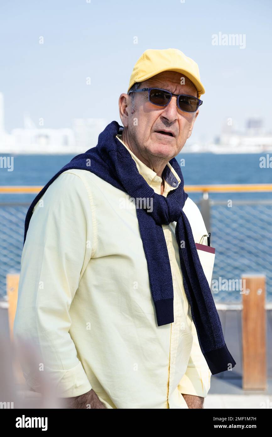 Senior man walking along a promenade alongside a marina Stock Photo - Alamy