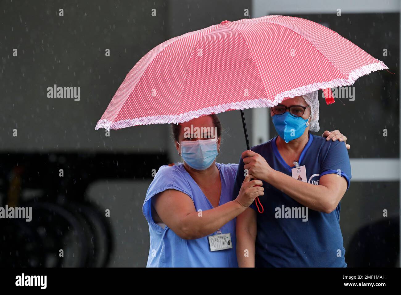 Healthcare workers wait in the rain as a patient suspected of having ...