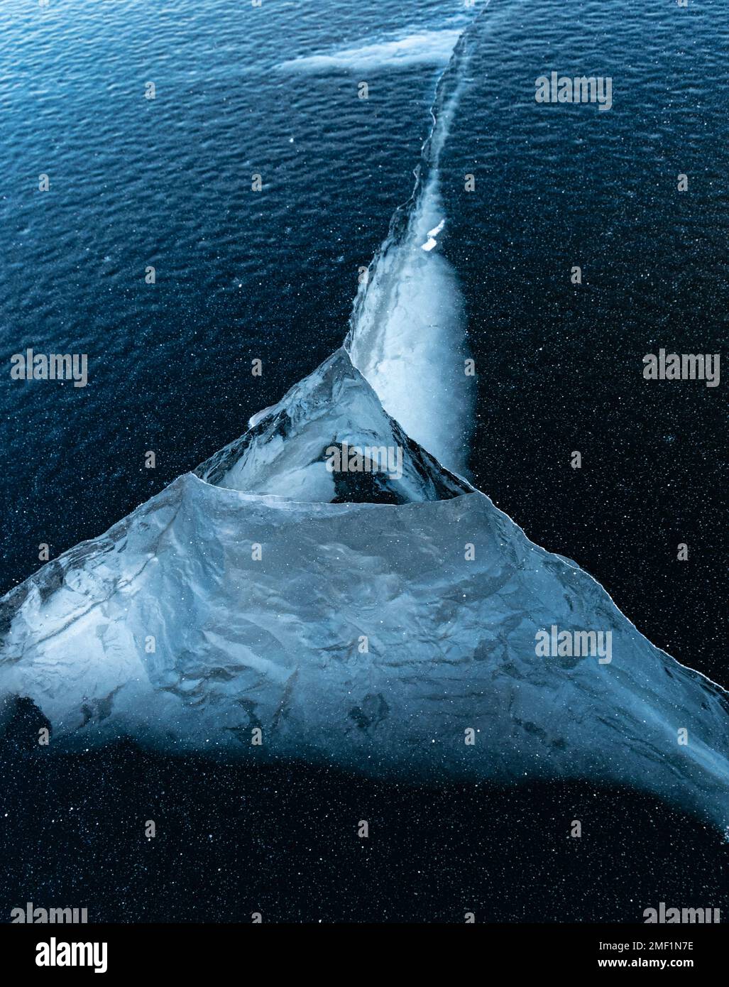 The cracked ice background. Blue transparent ice deep cracks top view ...