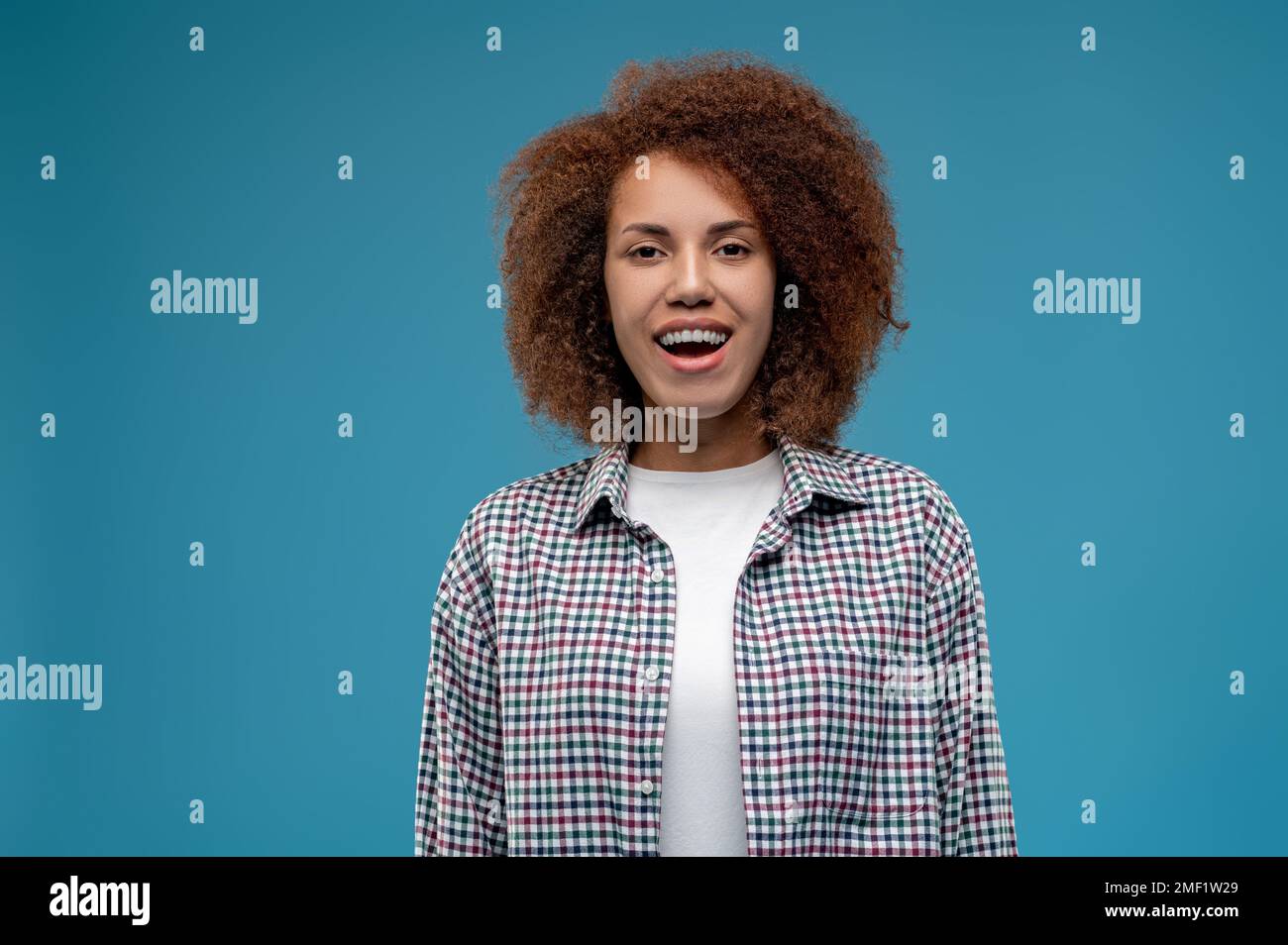 Curly-haired young woman looking contented and smiling Stock Photo - Alamy